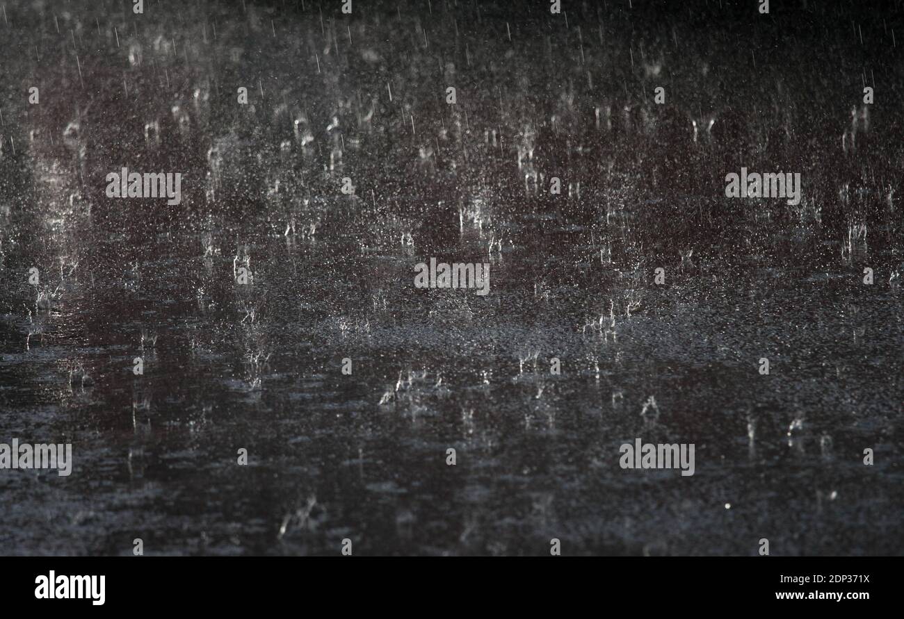 Heavy rain during a cloud burst with rain drops bouncing off the water ...