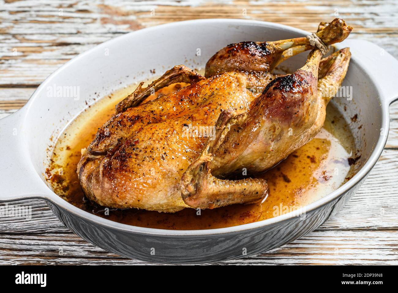Baked whole farm duck in a baking dish. White wooden background. Top ...