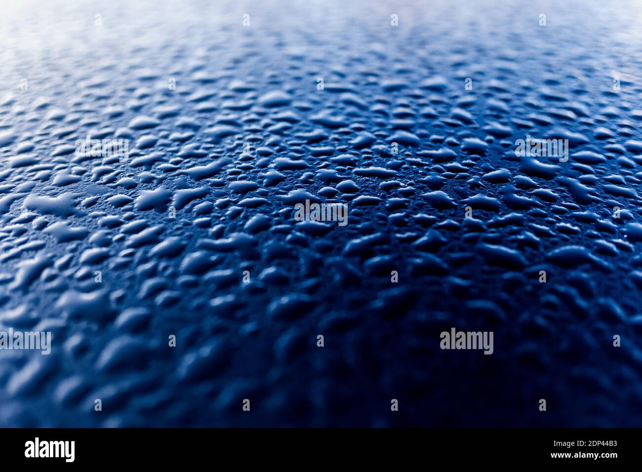 Bluish background of thick drops of water on a smooth and cool surface ...