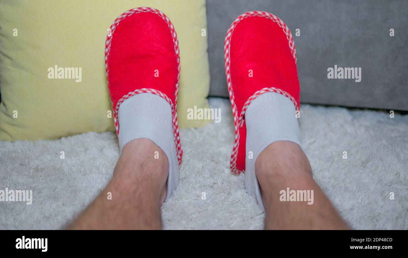 A man in home comfort,legs in slippers,a man sits on a warm rug,red ...