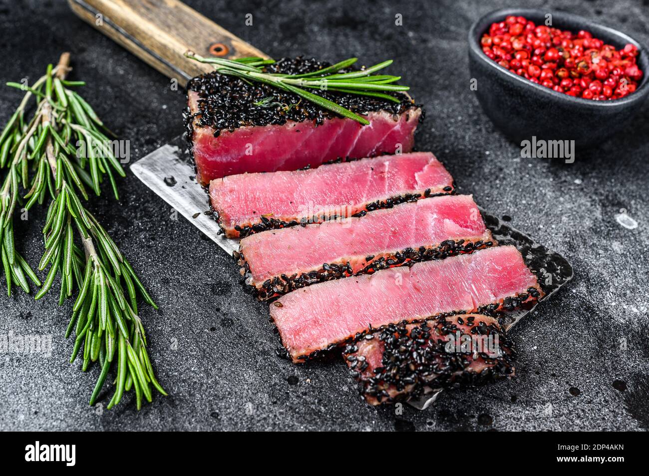 Rare Ahi tuna steak slices on a meat cleaver. Black background. Top ...