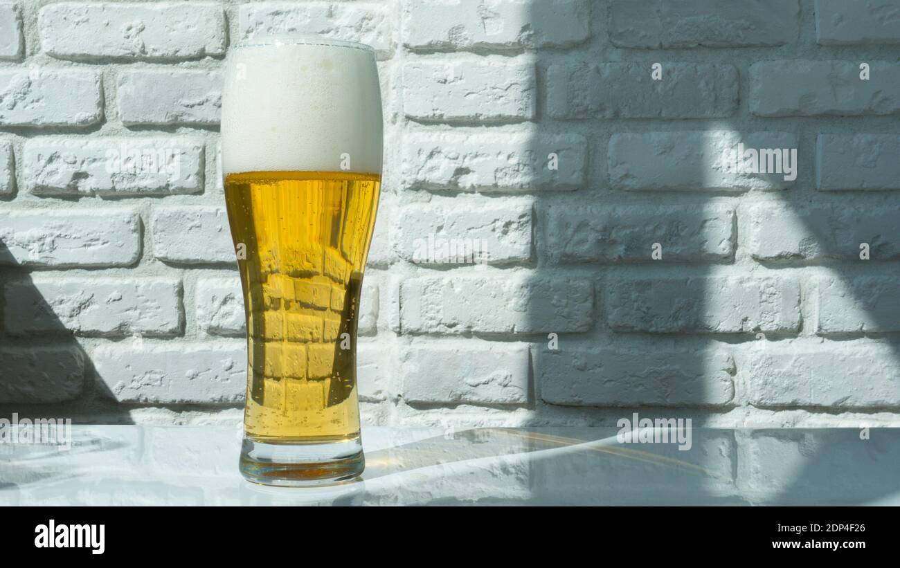 Glass of beer on a white brick wall background Stock Photo - Alamy