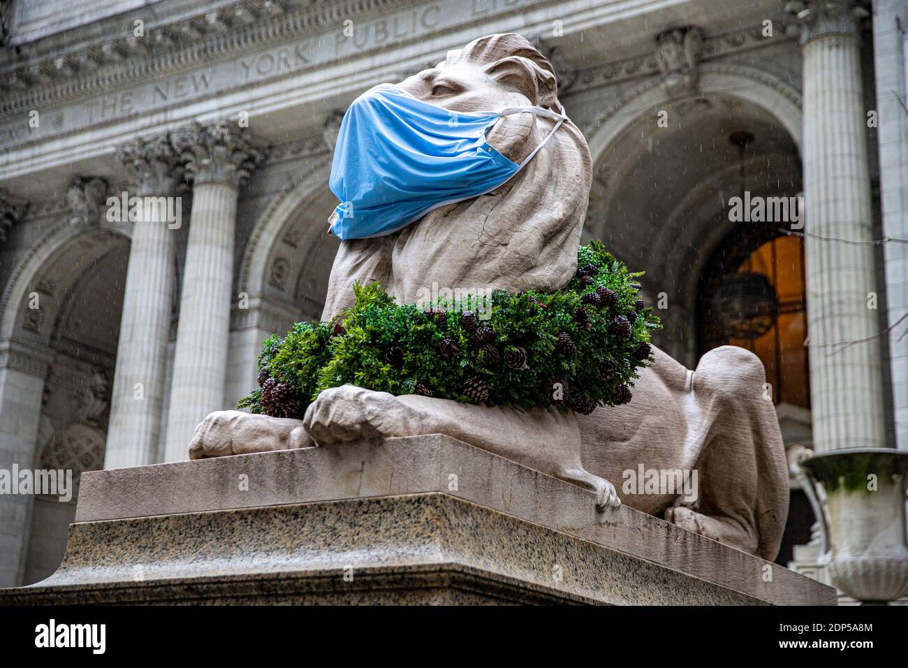 The statue of Fortitude the lion wears a mask and Christmas wreath ...