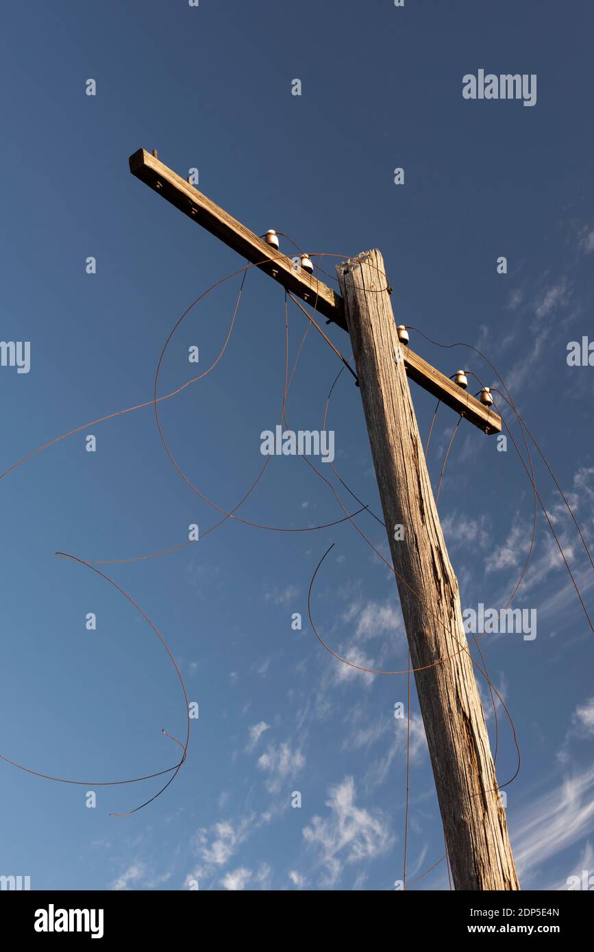 Old wooden electric pole with rusty broken wires with deep blue sky ...
