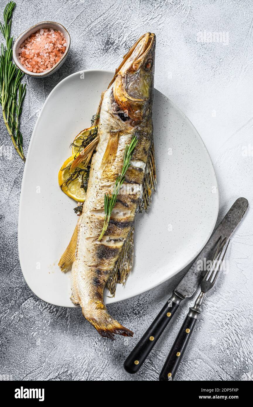 Grilled Zander, walleye fish with herbs and lemon on a plate. Gray ...