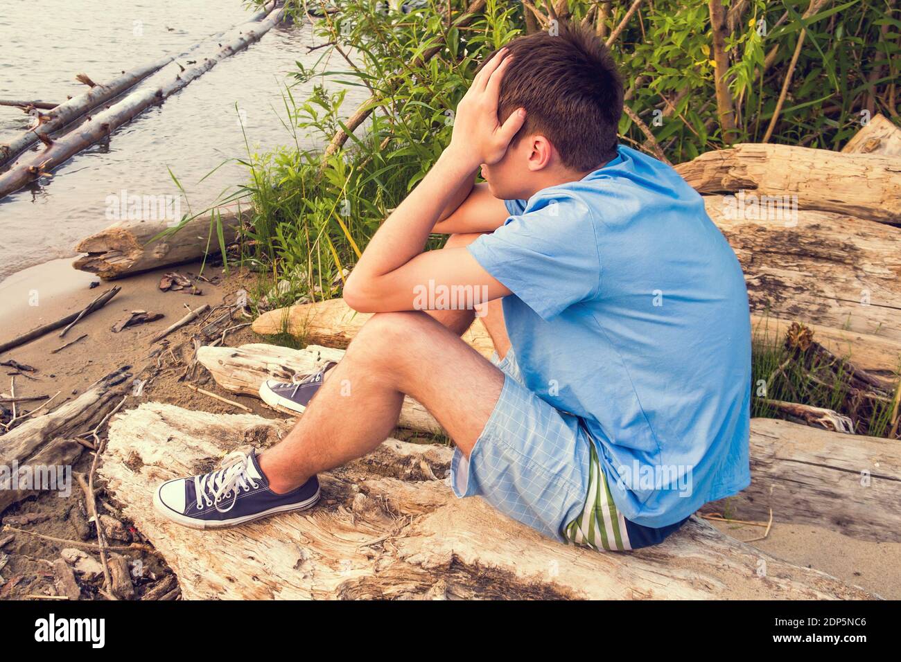 Toned Photo of Sad Young Man sit on the Log outdoor Stock Photo - Alamy