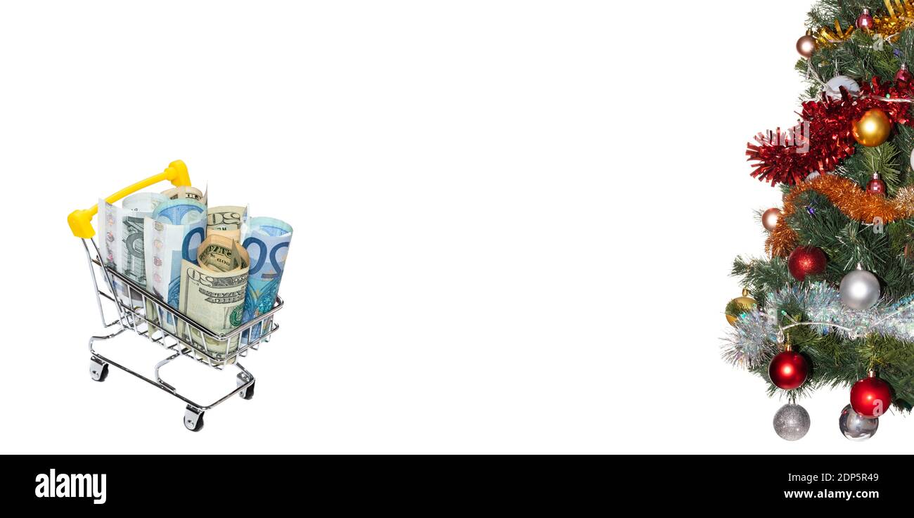 Shopping cart full of euro, dollar bills next to Christmas tree ...