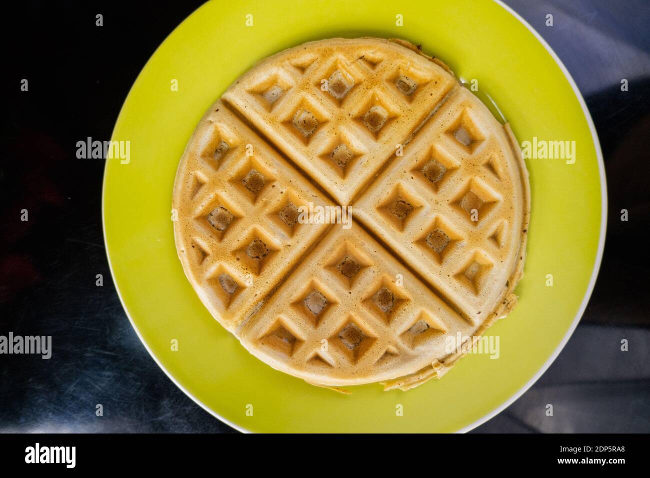 Fresh round waffle on a yellow plate from above Stock Photo - Alamy