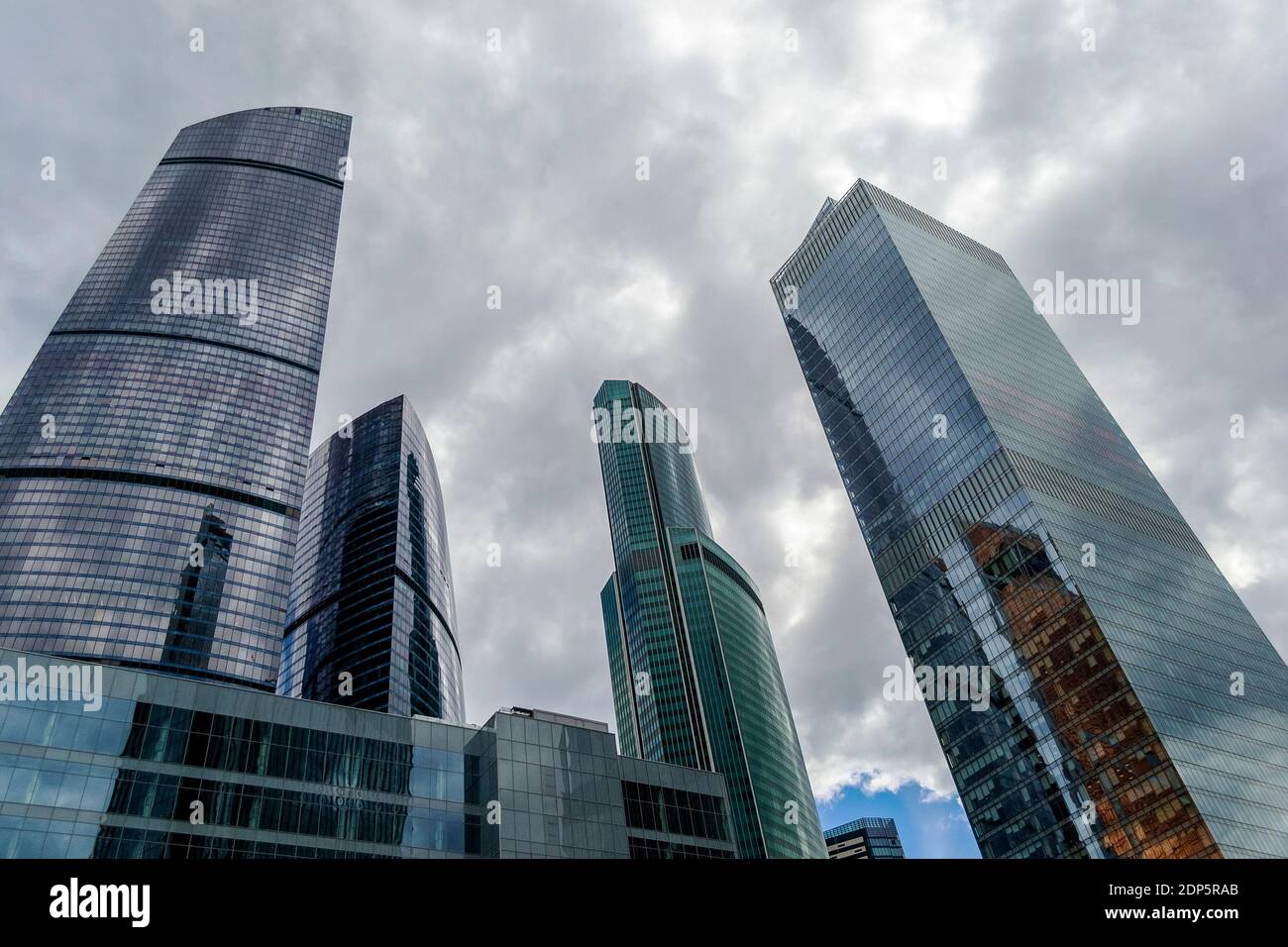 Glass modern skyscraper buildings opposite dark cloudy and stormy sky ...