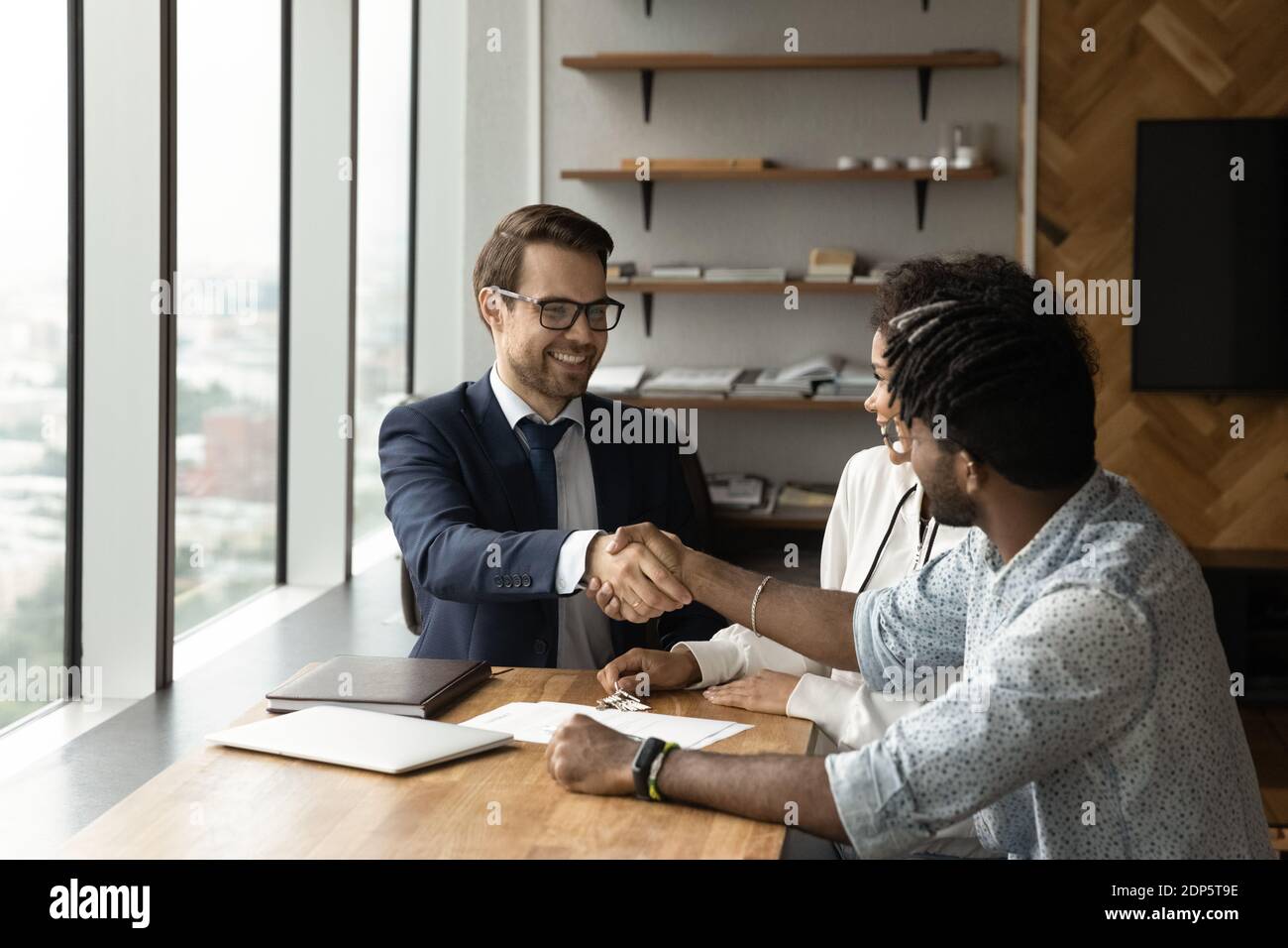 Male realtor handshake biracial couple clients at meeting Stock Photo ...