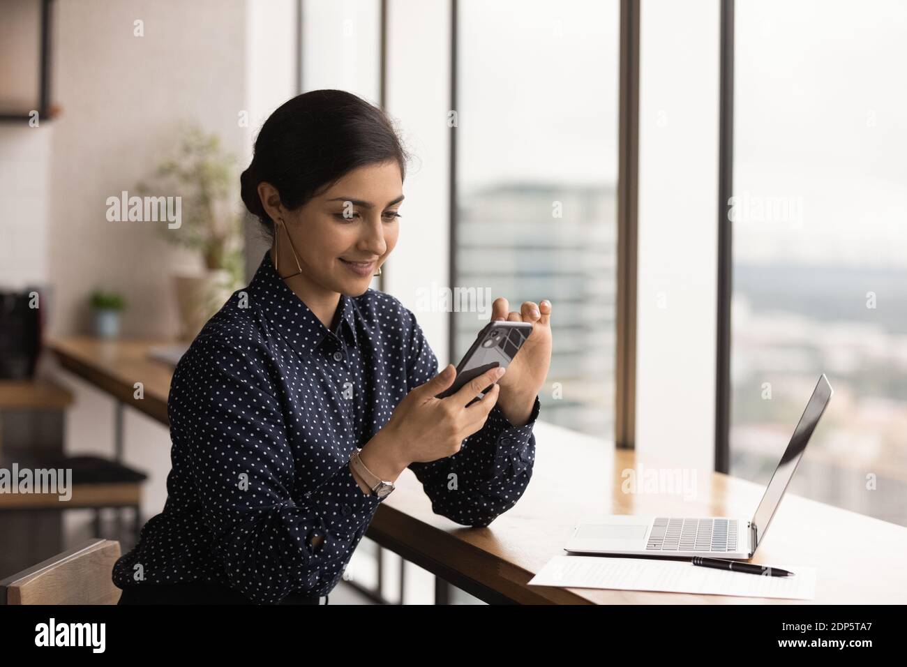 Smiling Indian woman use smartphone at workplace Stock Photo - Alamy