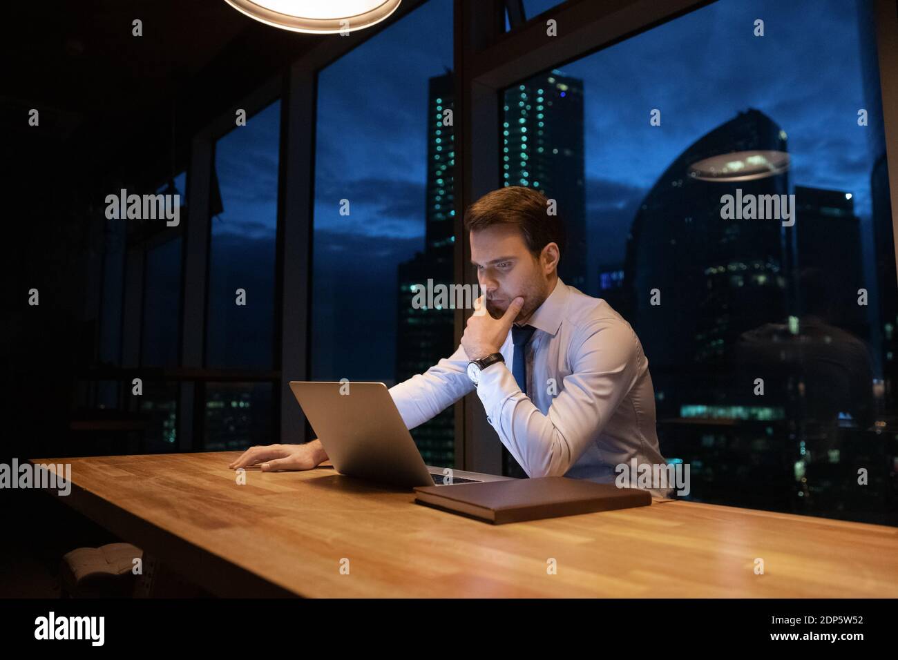 Pensive male employee work in office late hours Stock Photo - Alamy