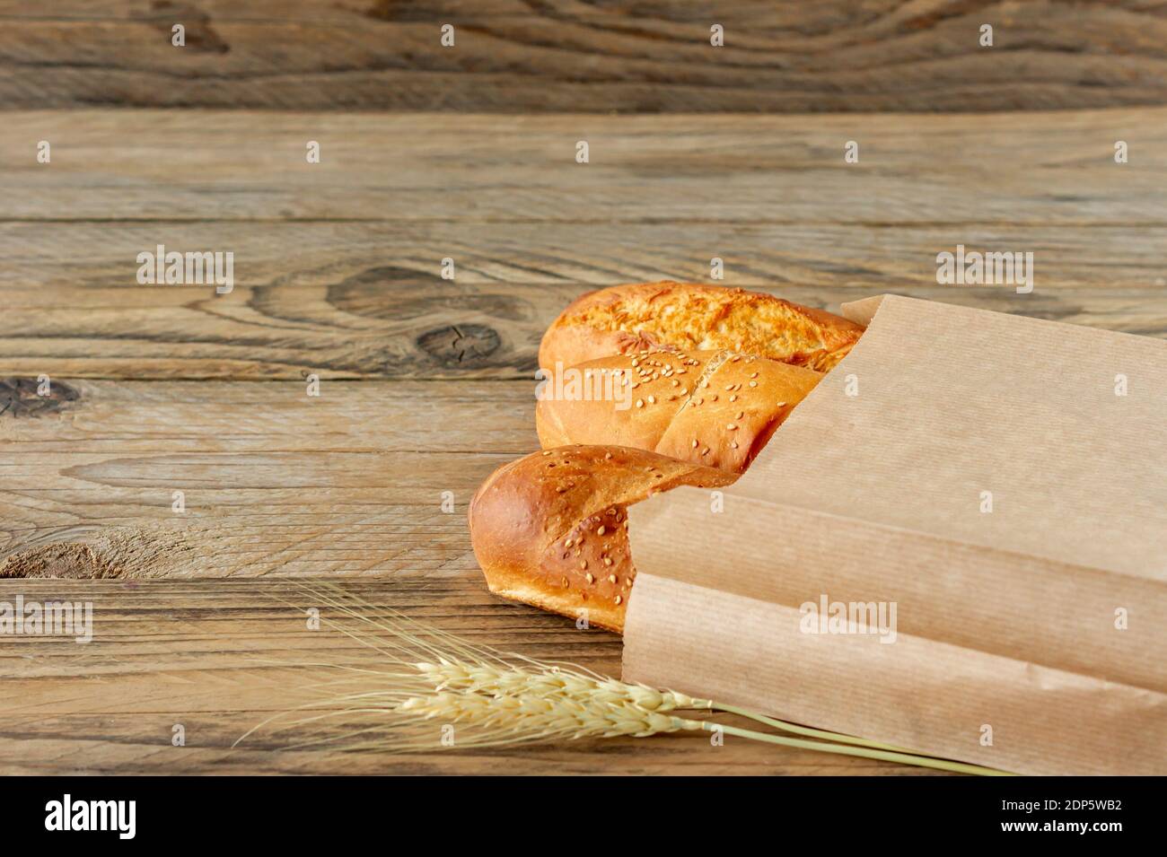 arranged french baguettes in paper bag and wheat on rustic wooden ...