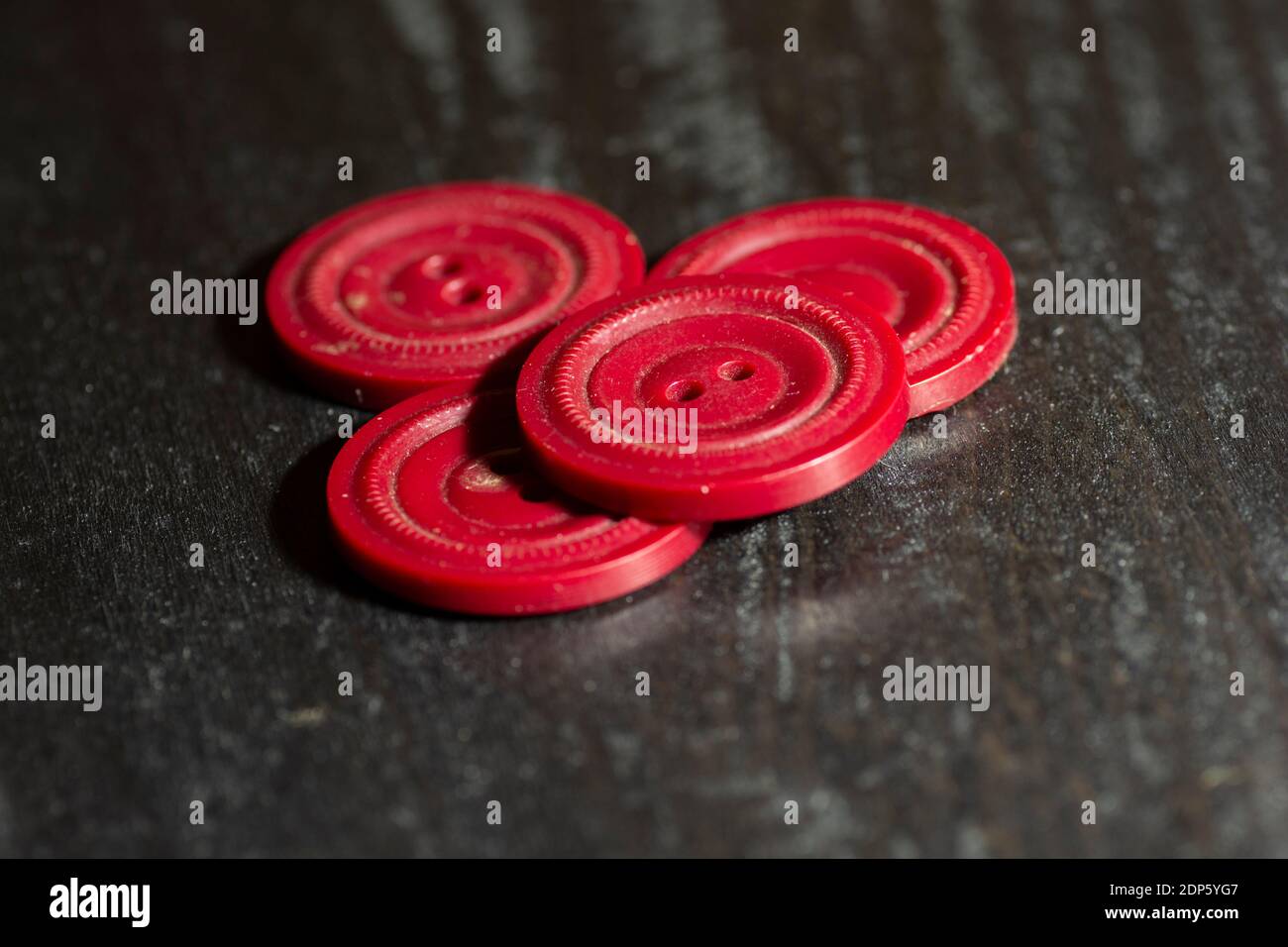 Red plastic sewing buttons isolated on dark background. Stacked round ...
