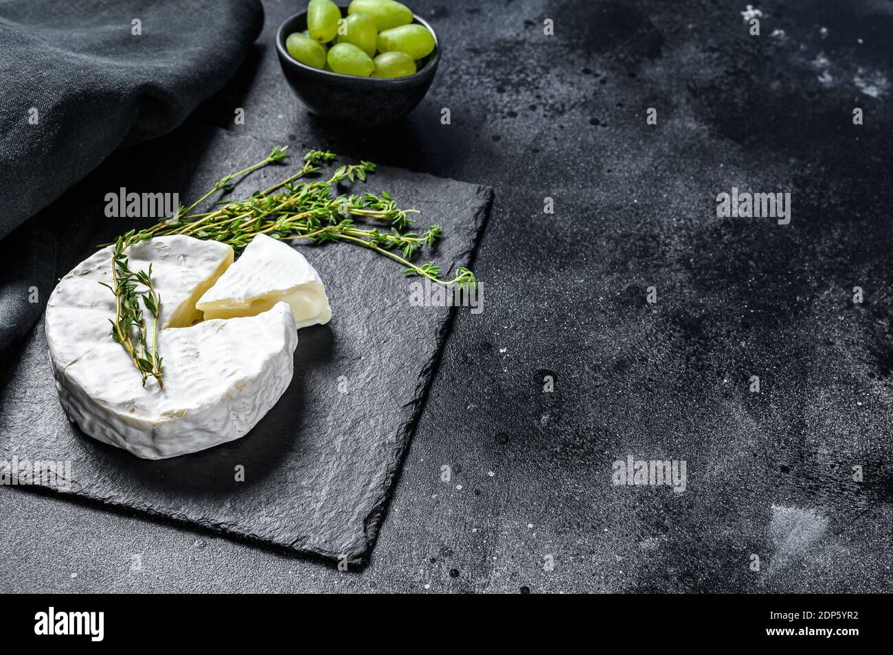 French Brie cheese with grapes. Black background. Top view. Copy space ...