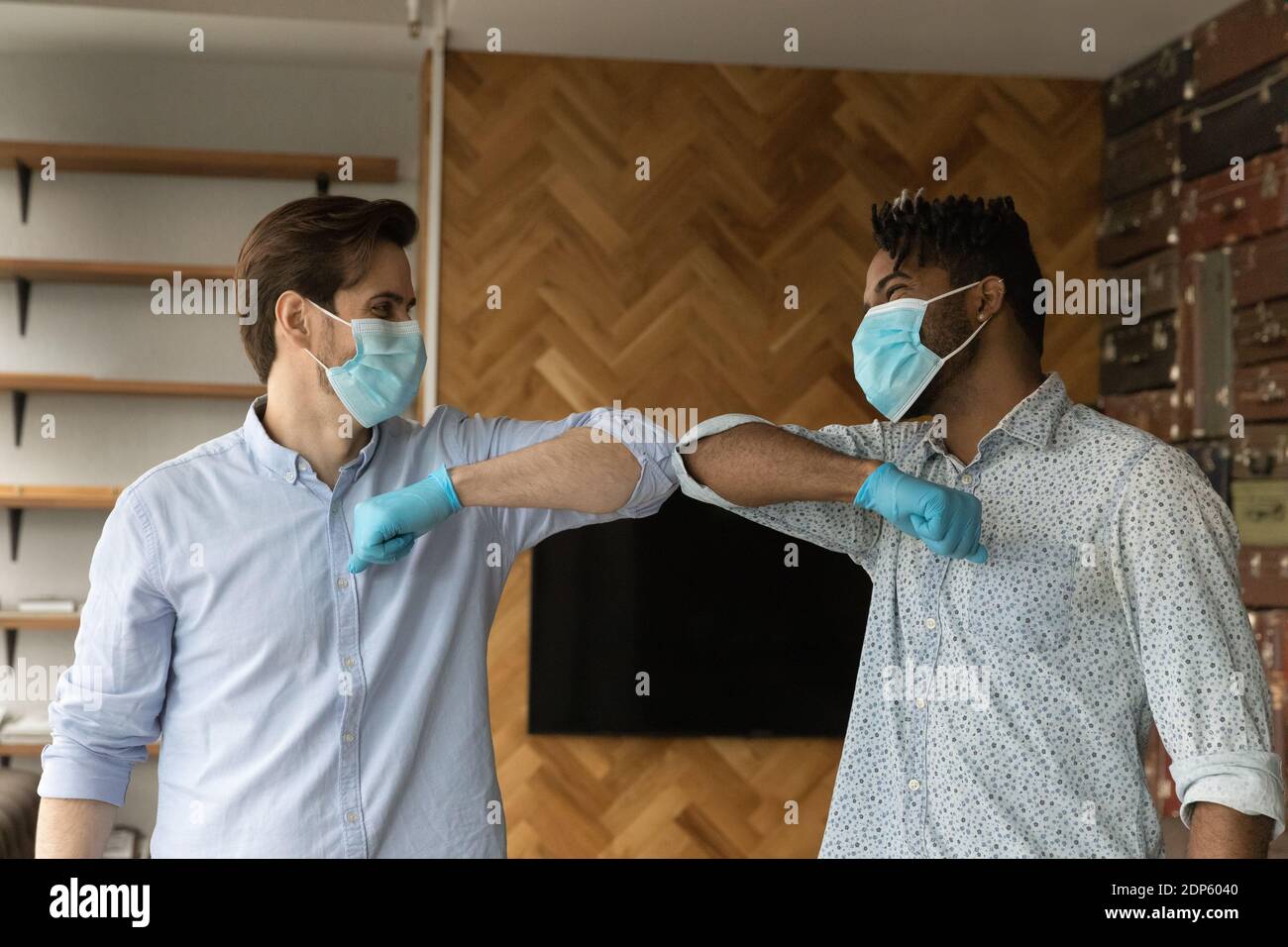 Smiling diverse men in masks greeting touching elbows Stock Photo - Alamy