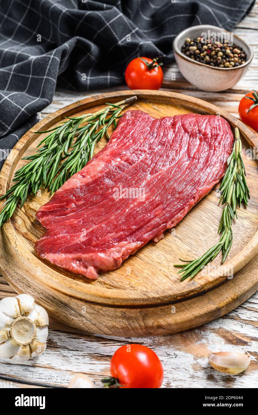 Raw Flank steak on a cutting board. Fresh Marble beef meat black Angus. White wooden background ...