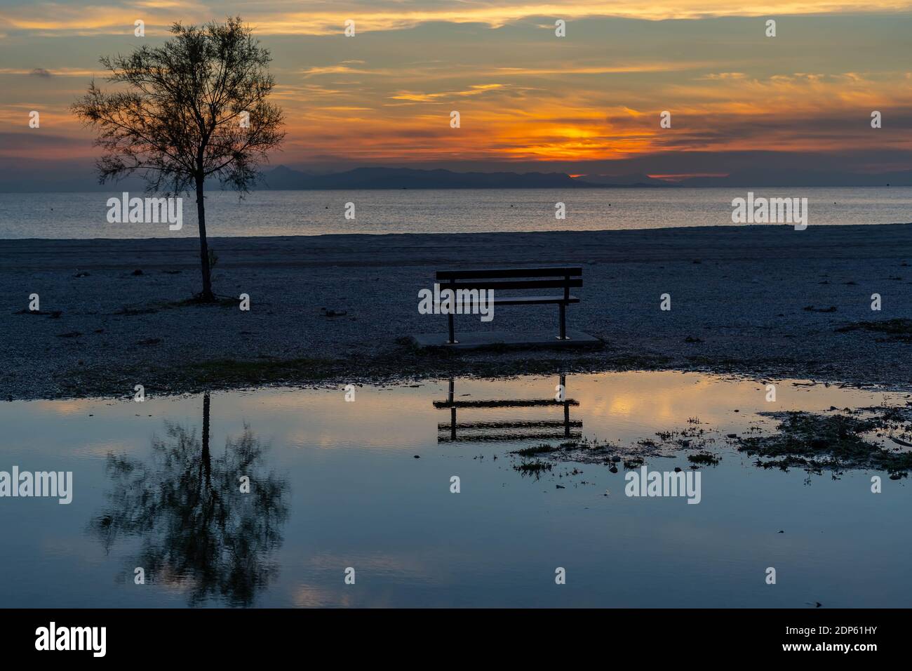 Lonely bench in front of a sunset at Greece Stock Photo - Alamy