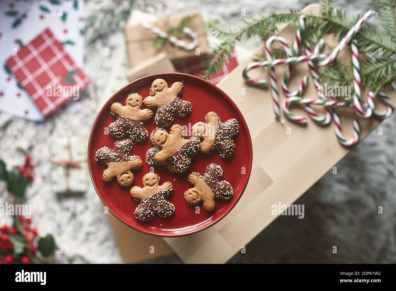 A top view of gingerbread cookies on a red plate on a wooden board with ...
