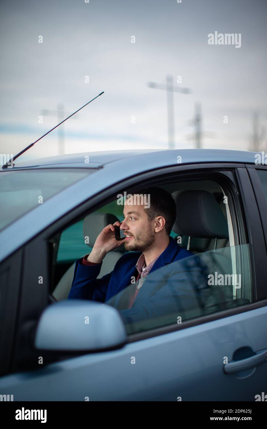 Handsome young man calling on his cellphone while at the wheel of his ...