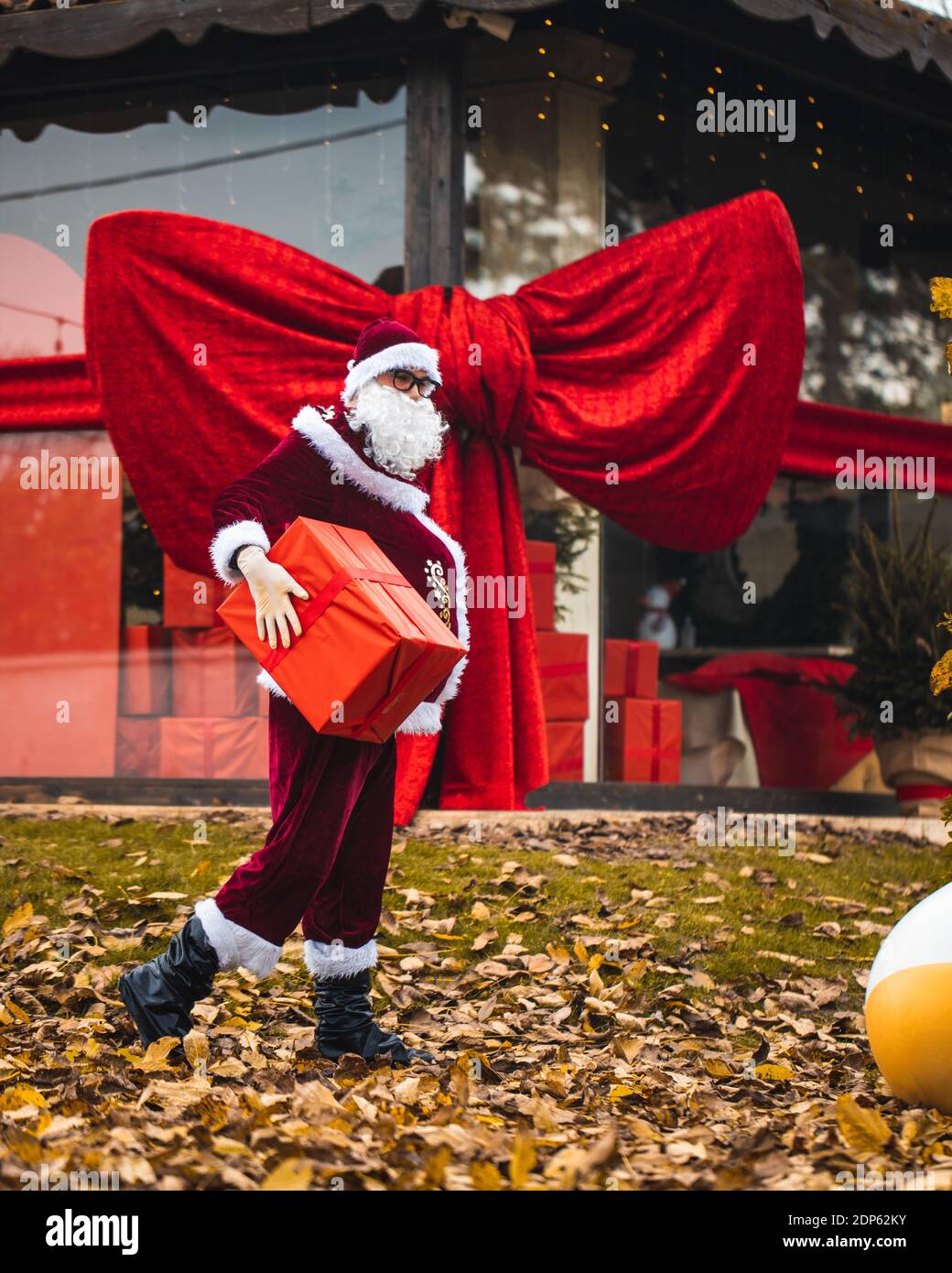 A Santa Claus wearing glasses and holding a big red gift box Stock ...