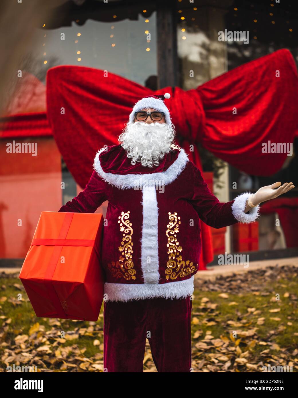 A Santa Claus wearing glasses and holding a big red gift box Stock ...