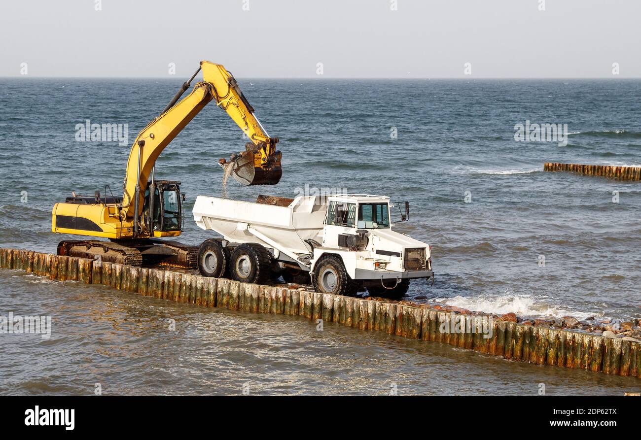 excavator loading soil into a large truck during the construction of a ...