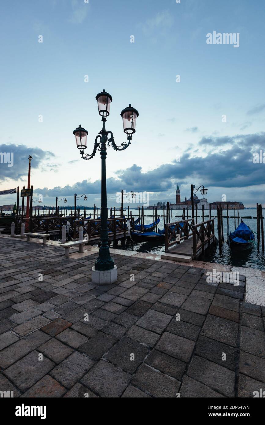 A row of moored gondole at the Traghetto Gondola Molo jetty with views ...