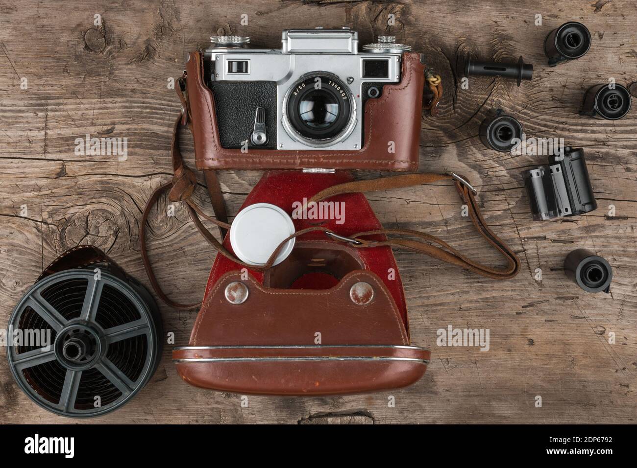 Retro camera in a brown leather case lies on a wooden table. Top view ...
