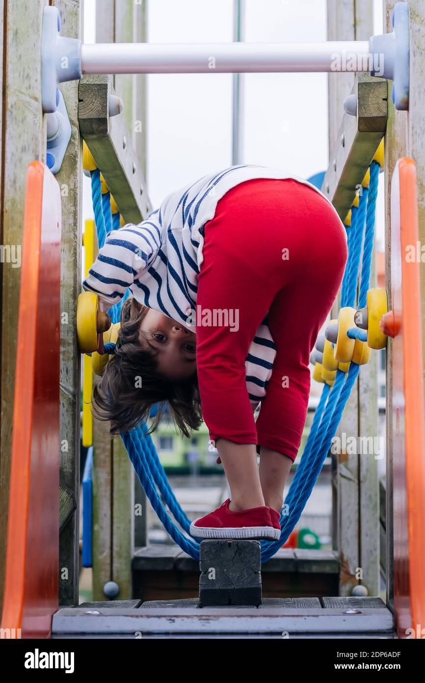 The picture shows a little girl playing on a playground turning her ...