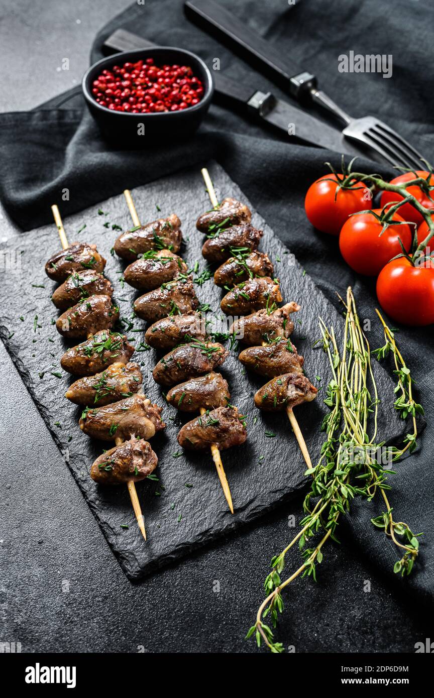 Grilled shish kebab with chicken hearts. Black background. Top view ...