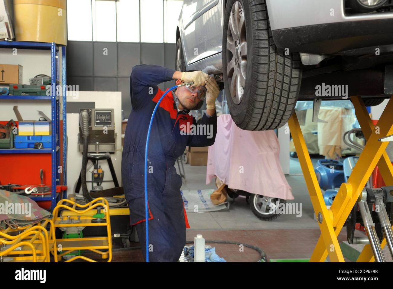 A concentrated European mechanic working on a car tire in a garage ...