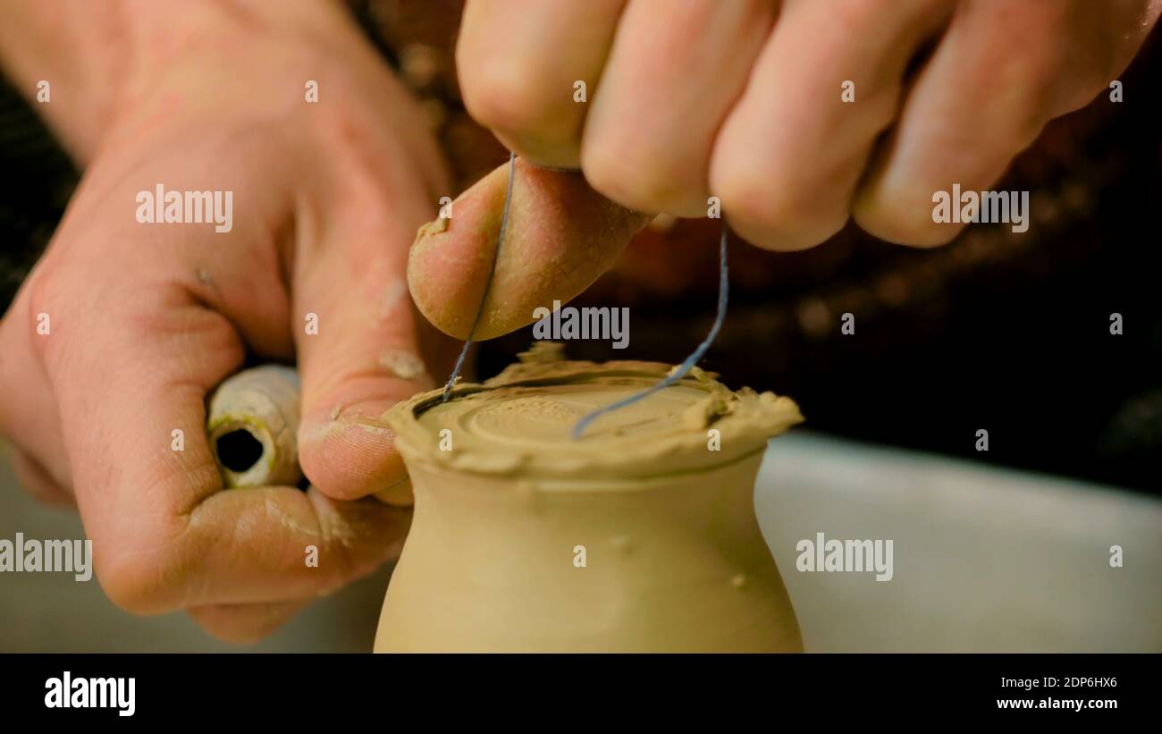Professional potter shaping mug with special tool in pottery workshop ...