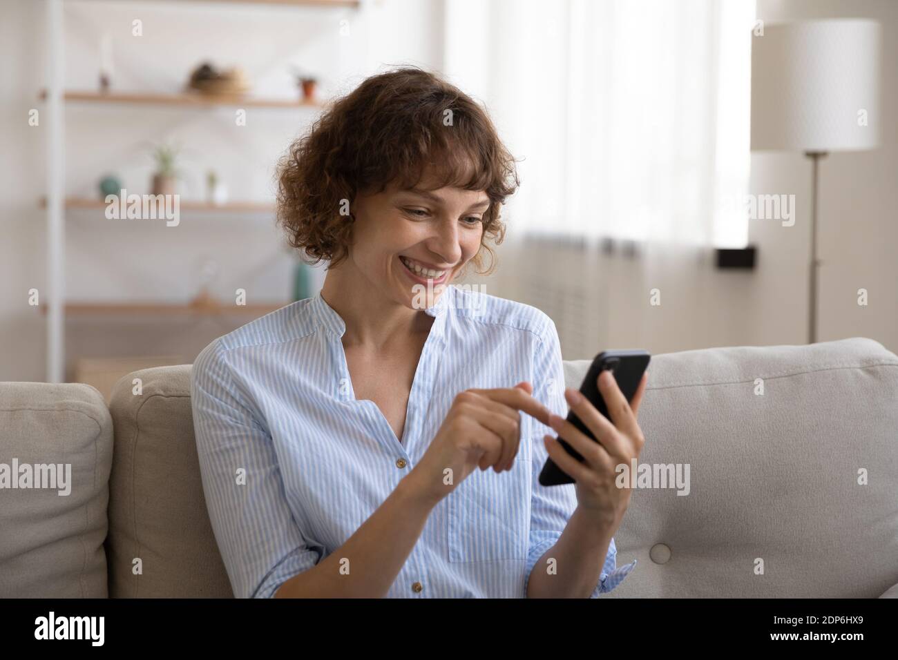 Smiling woman scrolling web pages on cell reading good news Stock Photo ...
