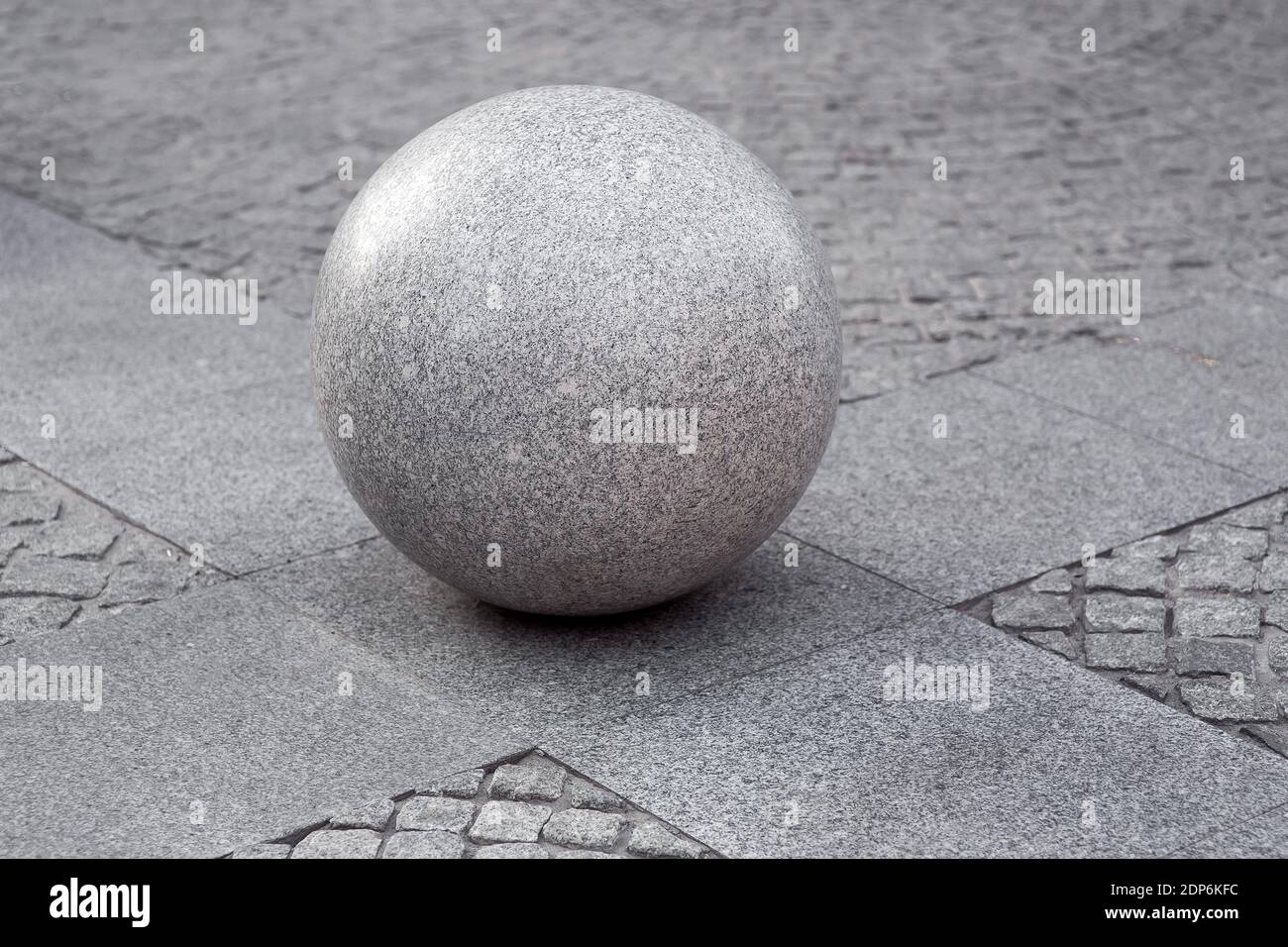gray granite ball on the pedestrian sidewalk on a paving square with ...