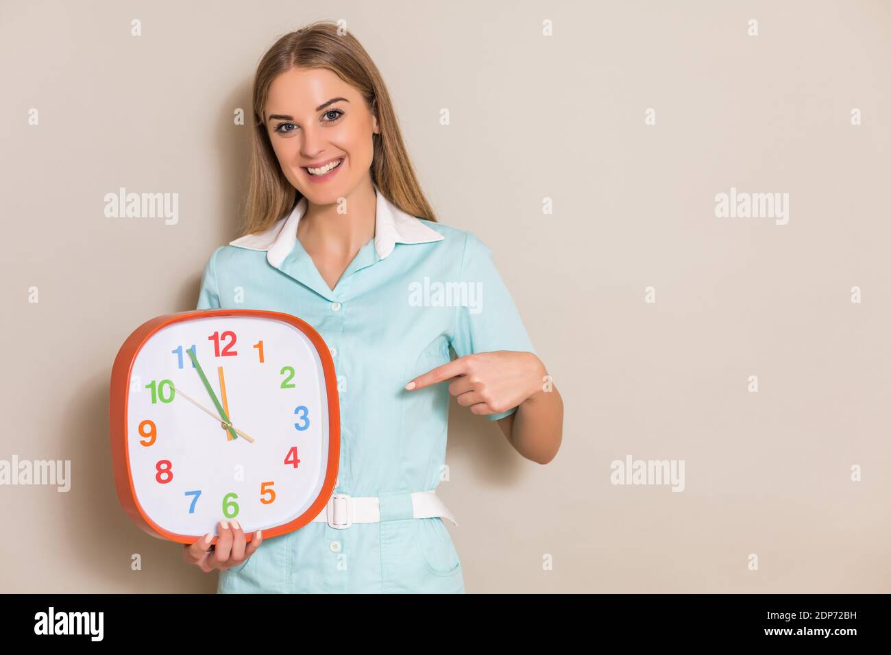 Portrait of medical nurse pointing at clock Stock Photo - Alamy