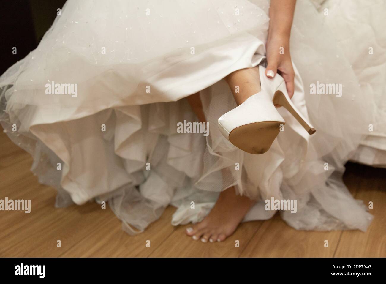 The bride putting on her white shoes on the wedding morning Stock Photo ...