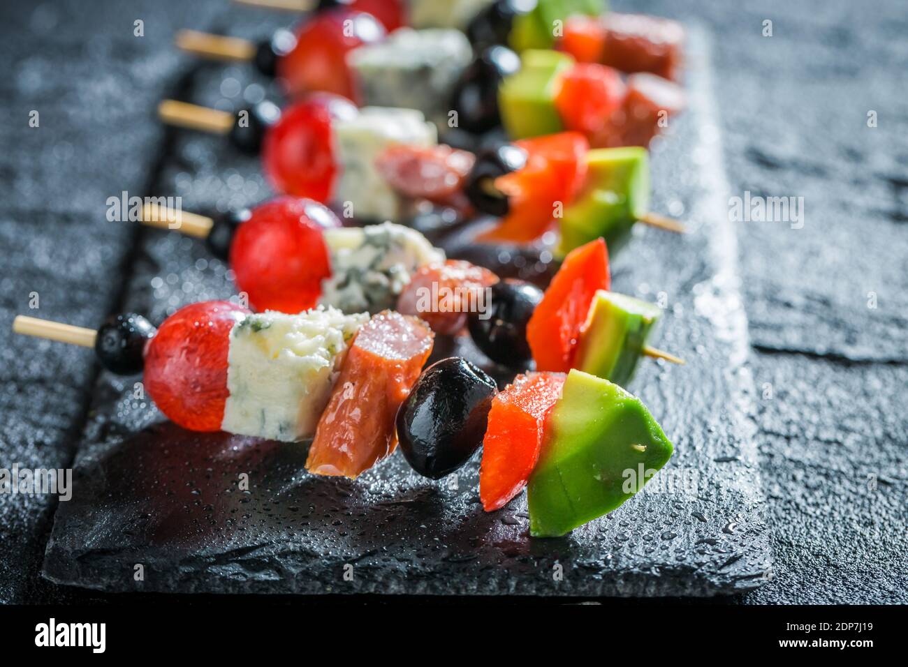 Closeup of various finger food with fresh ingredients on black rock ...