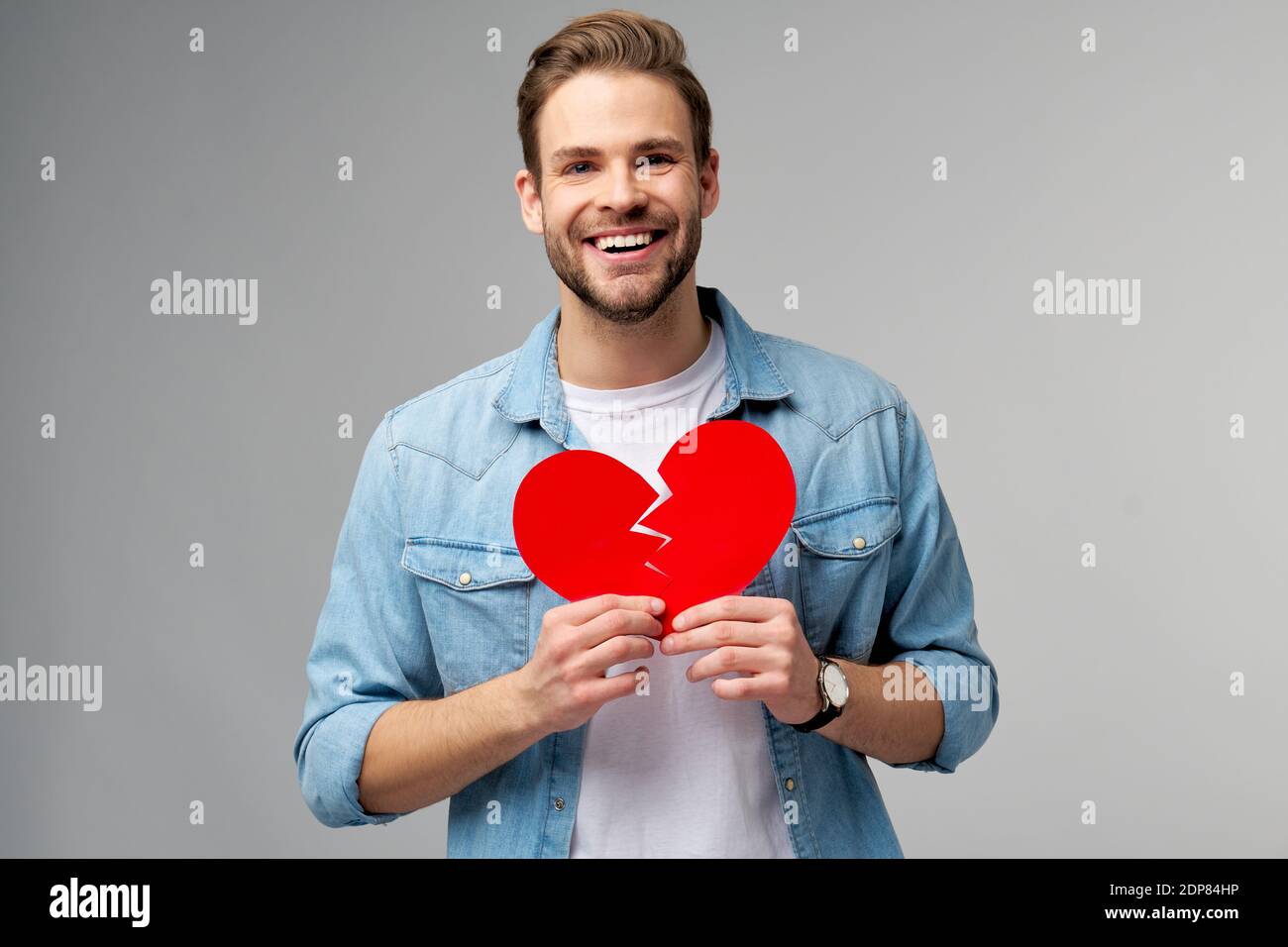 handsome young man holding broken paper red valentine heart standing ...