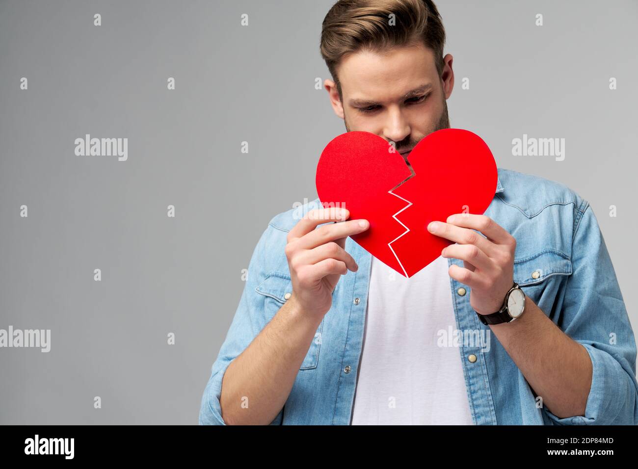 handsome young man holding broken paper red valentine heart standing ...