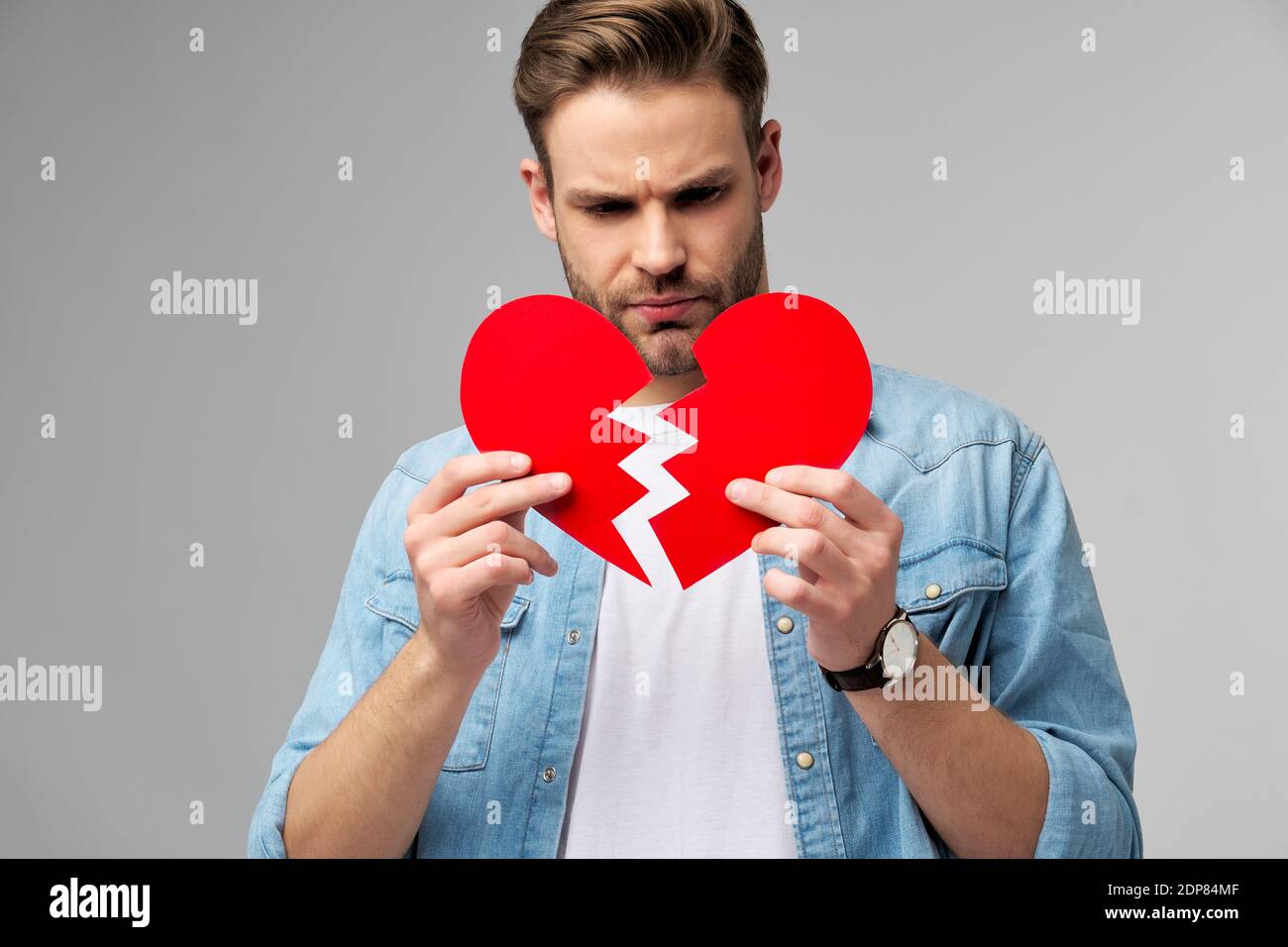 handsome young man holding broken paper red valentine heart standing ...