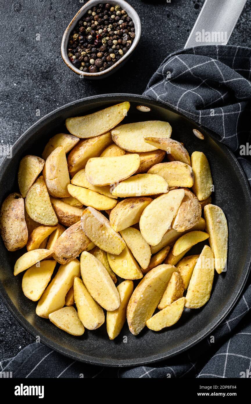 Frozen potato wedges in a pan. French fries. Black background. Top view ...