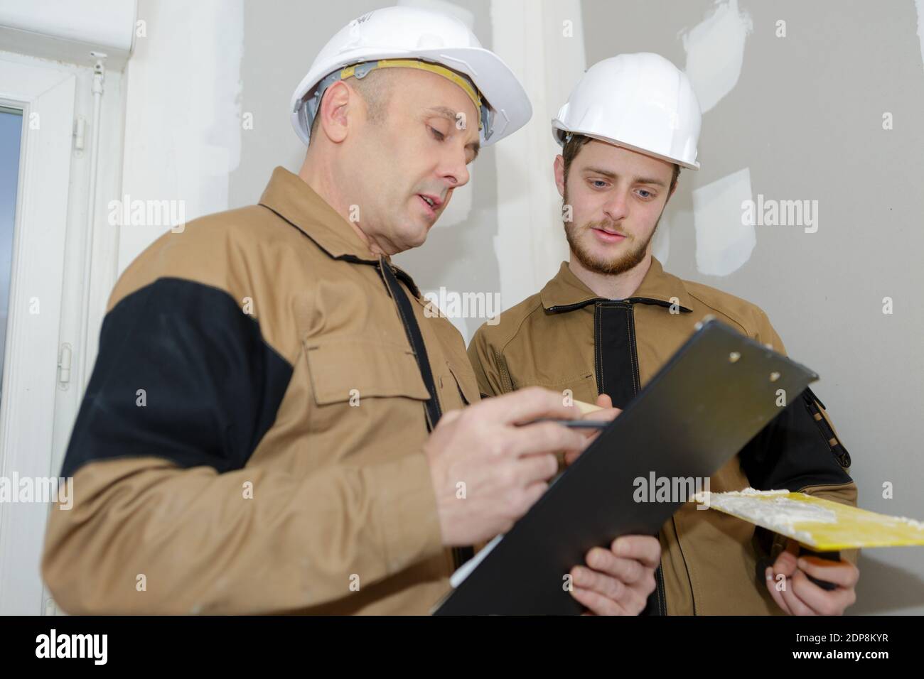 supervisor talking to young plasterer Stock Photo - Alamy