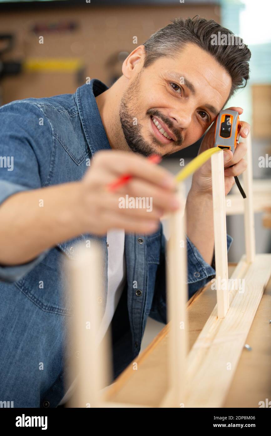 happy man measuring length of wood in his living room Stock Photo - Alamy