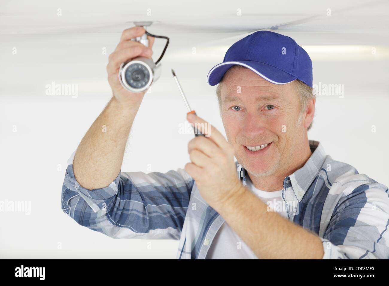 senior contractor installing overhead cctv camera Stock Photo - Alamy