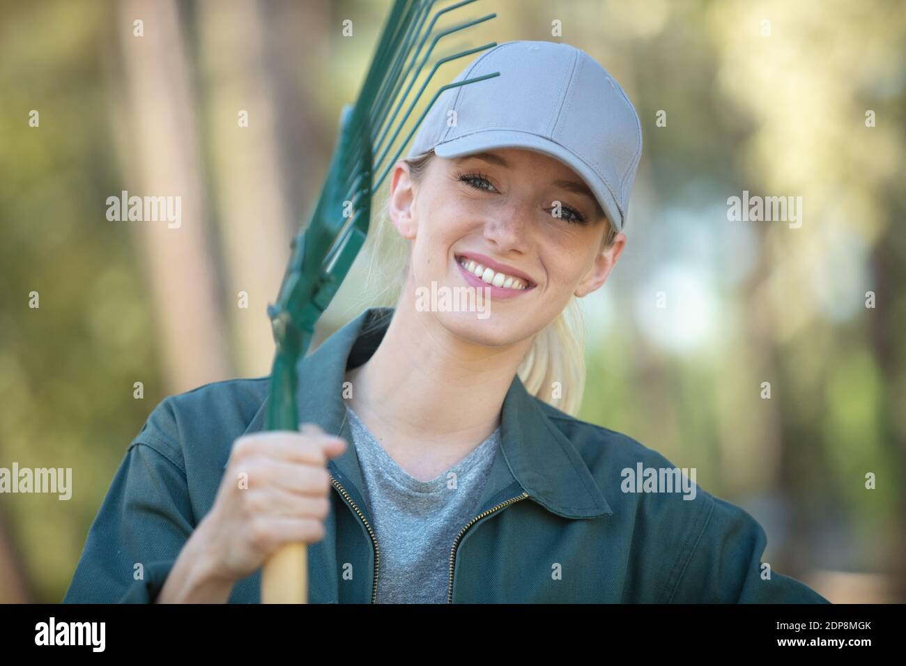 female gardener holding a rake standing in the garden Stock Photo - Alamy