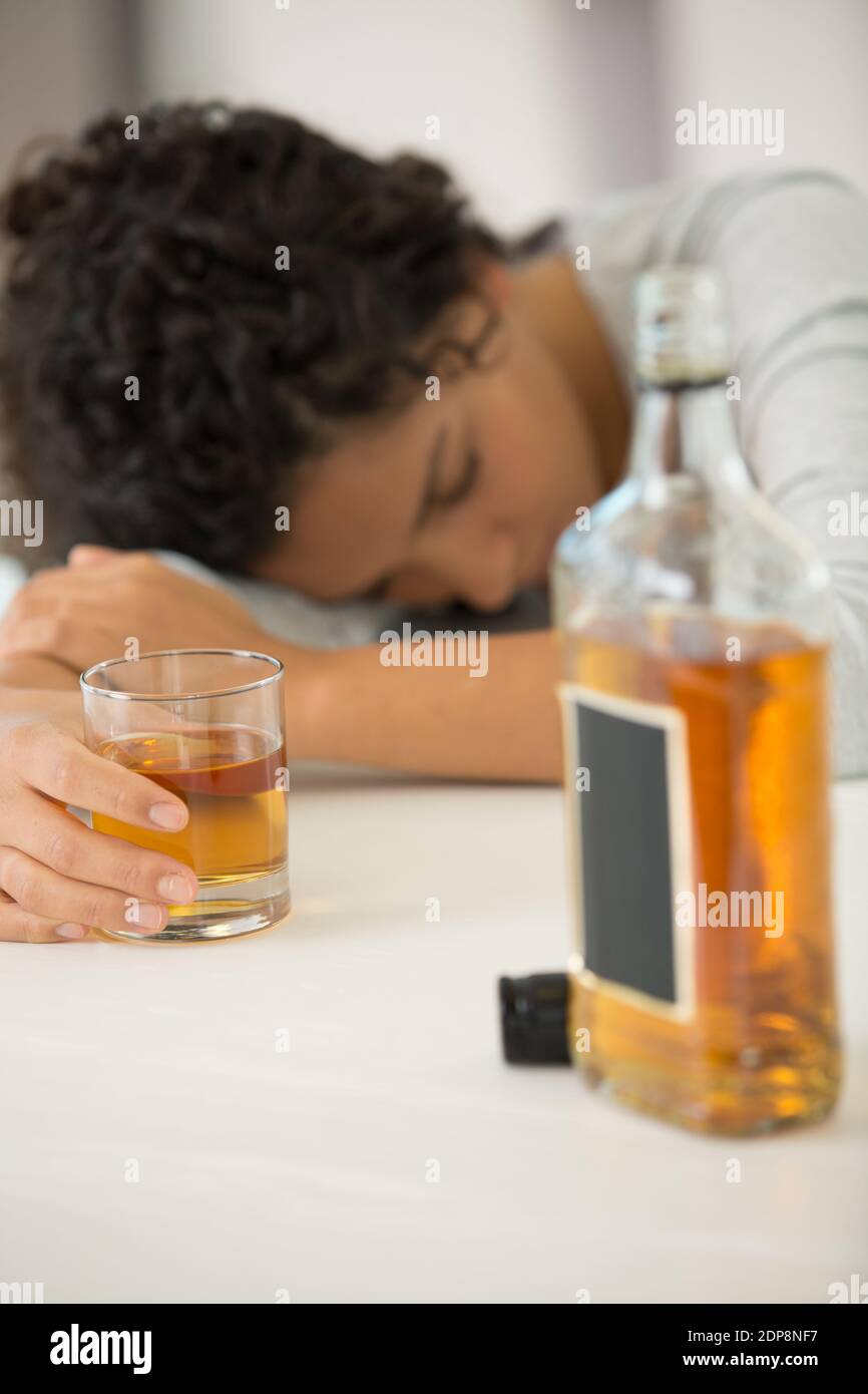 woman slumped over table still holding glass of whisky Stock Photo - Alamy