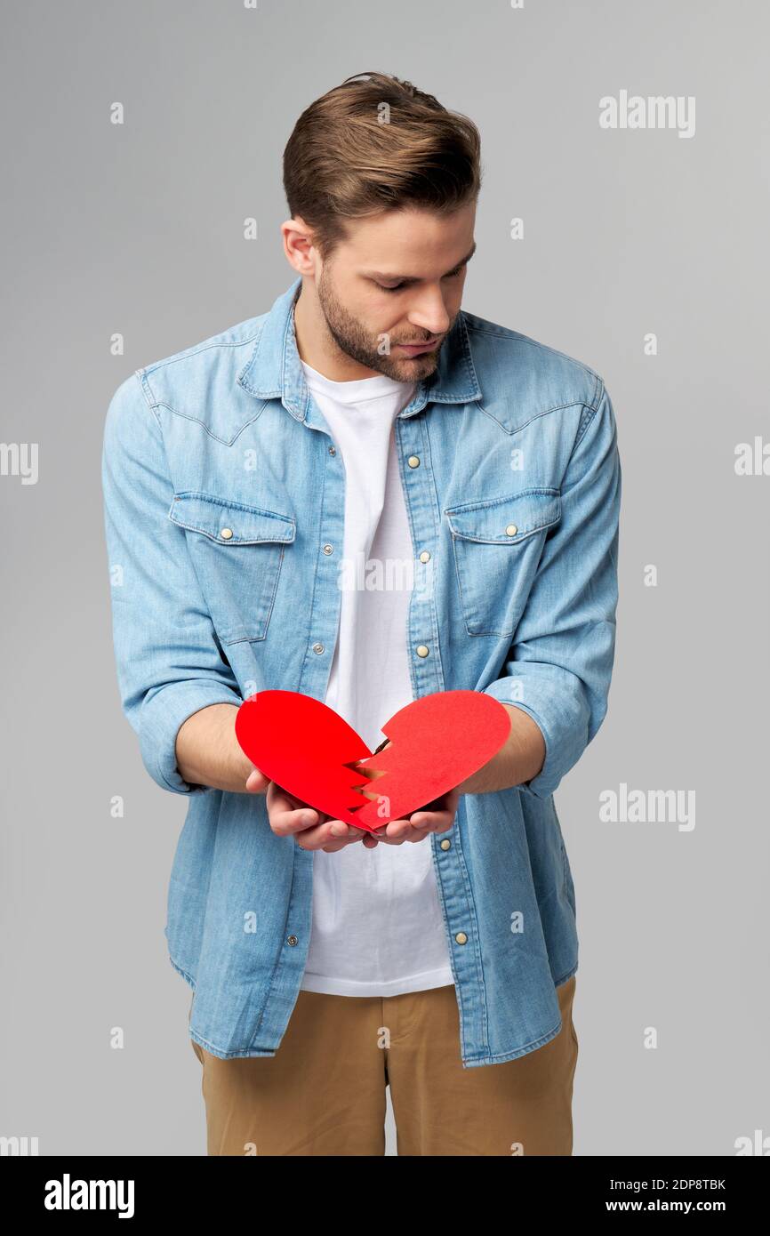 handsome young man holding broken paper red valentine heart standing ...
