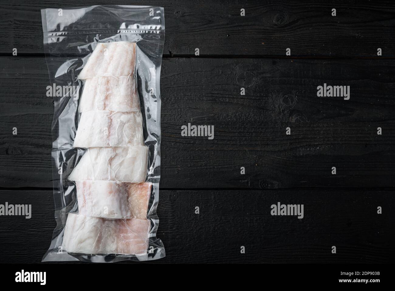 Raw haddock fish skinless plastic vacuum packaged, on black wooden ...