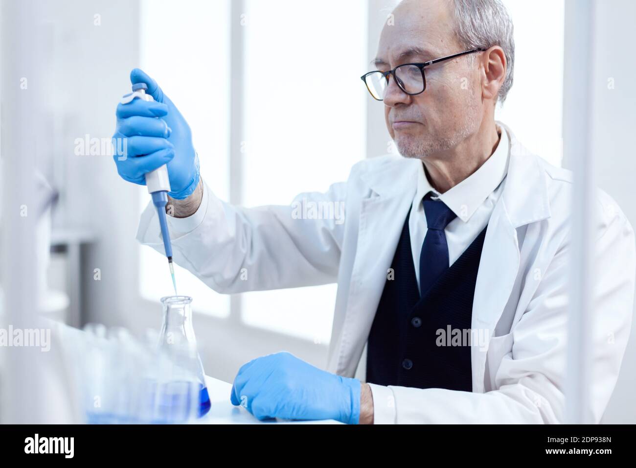 Elderly scientist doing pharmaceutical experiment using dropper pipette ...